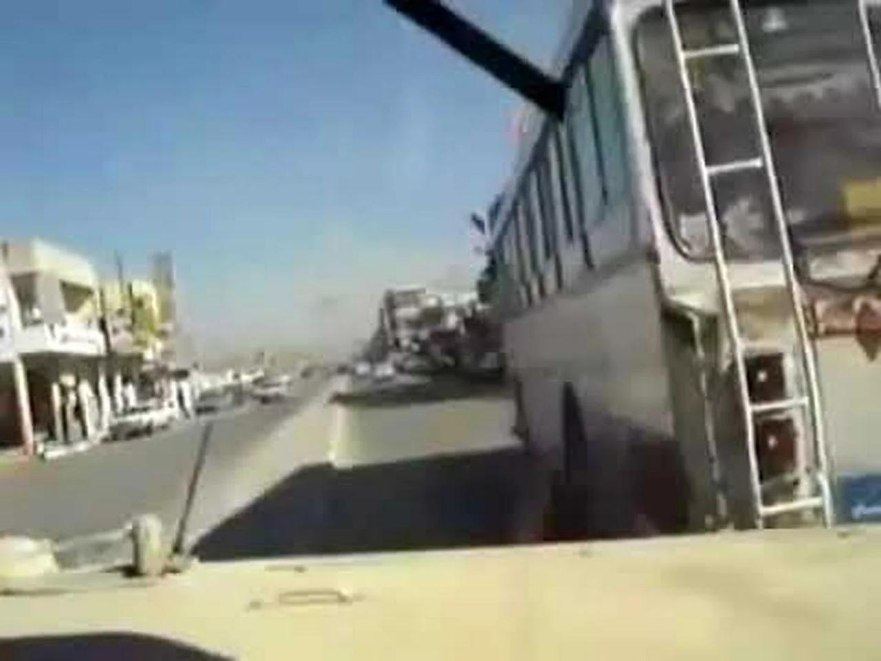 Military vehicle bumping cars driving through Middle East
